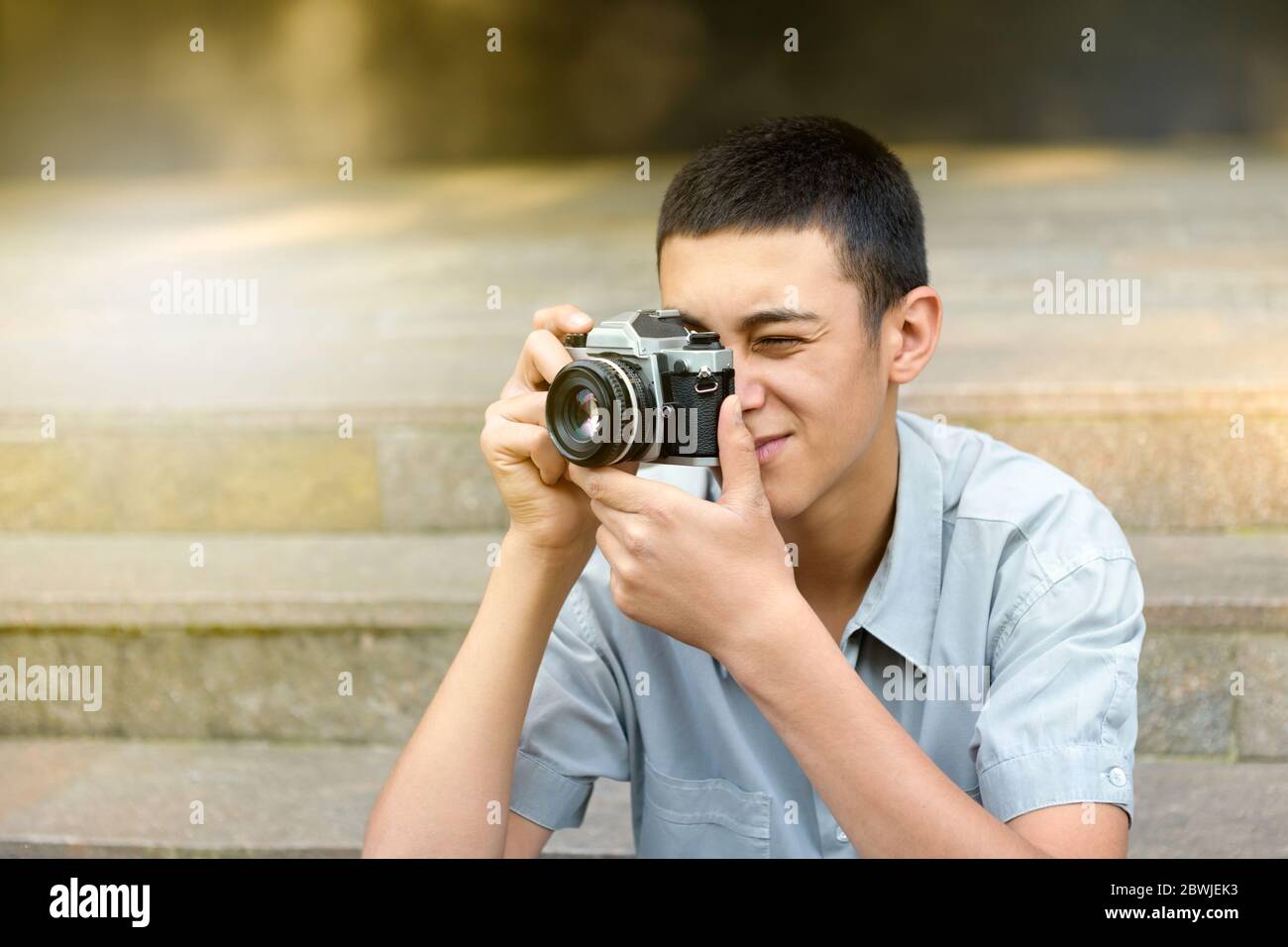 Young man taking photographs on his camera outdoors on urban steps ...