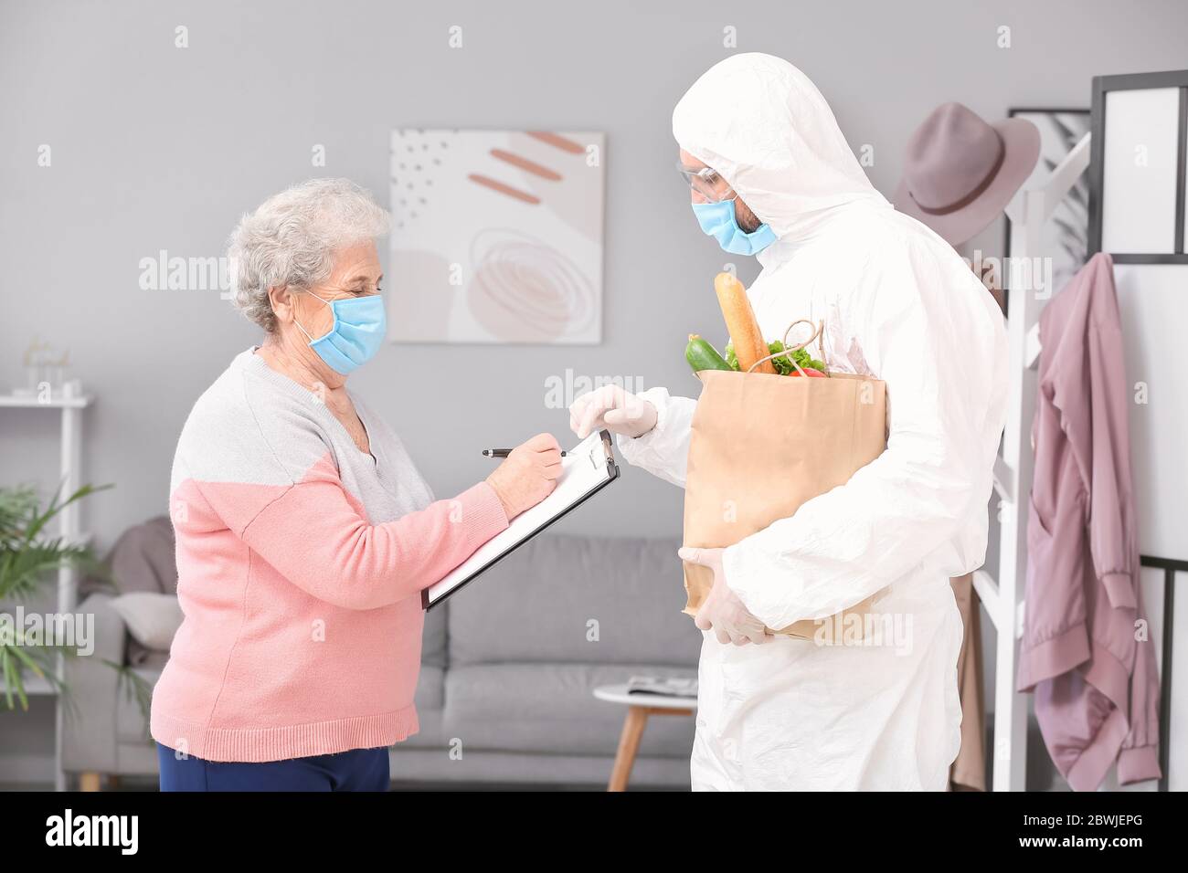 Senior woman receiving food from courier at home. Concept of epidemic ...