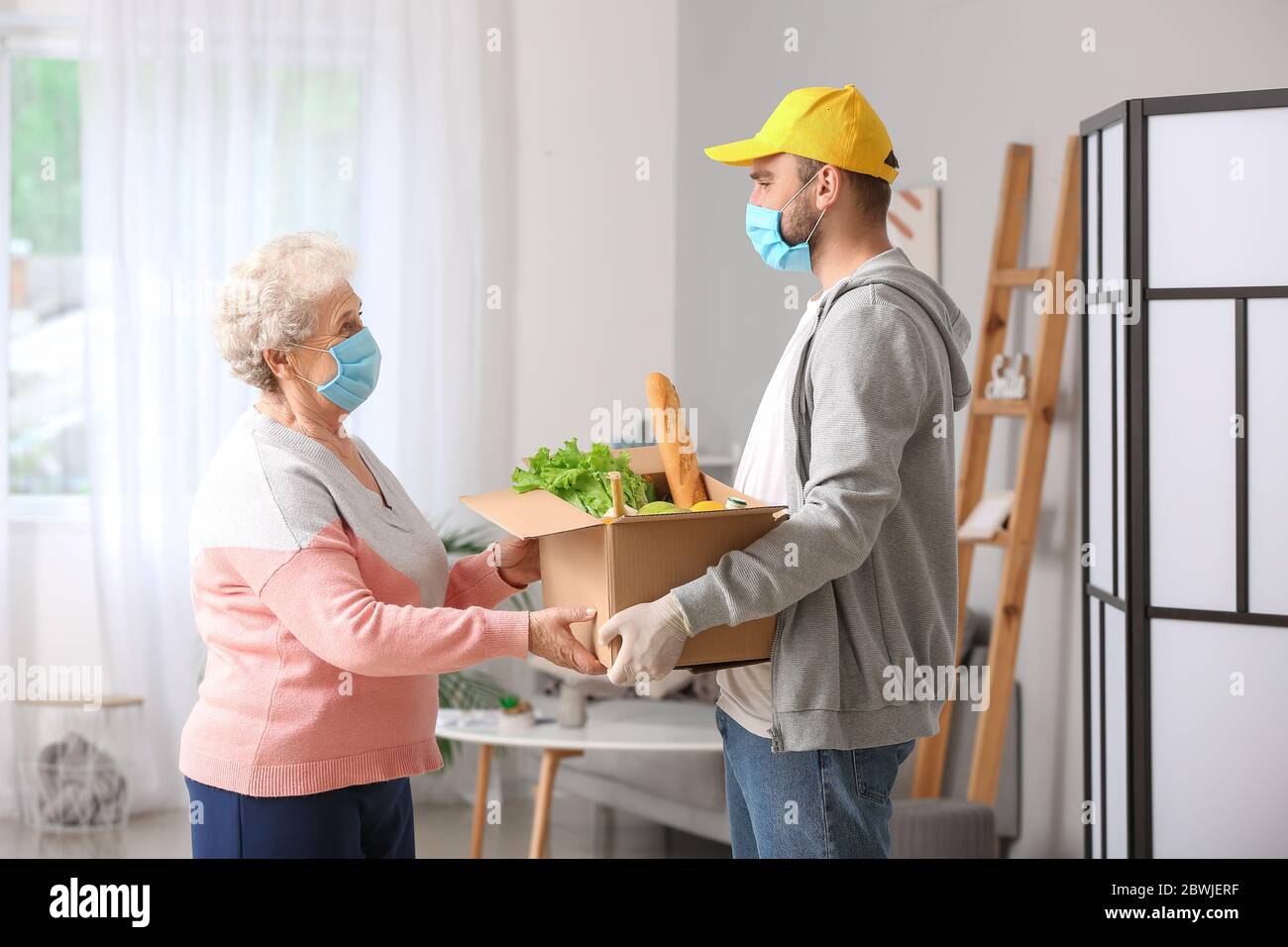 Senior woman receiving food from courier at home. Concept of epidemic ...