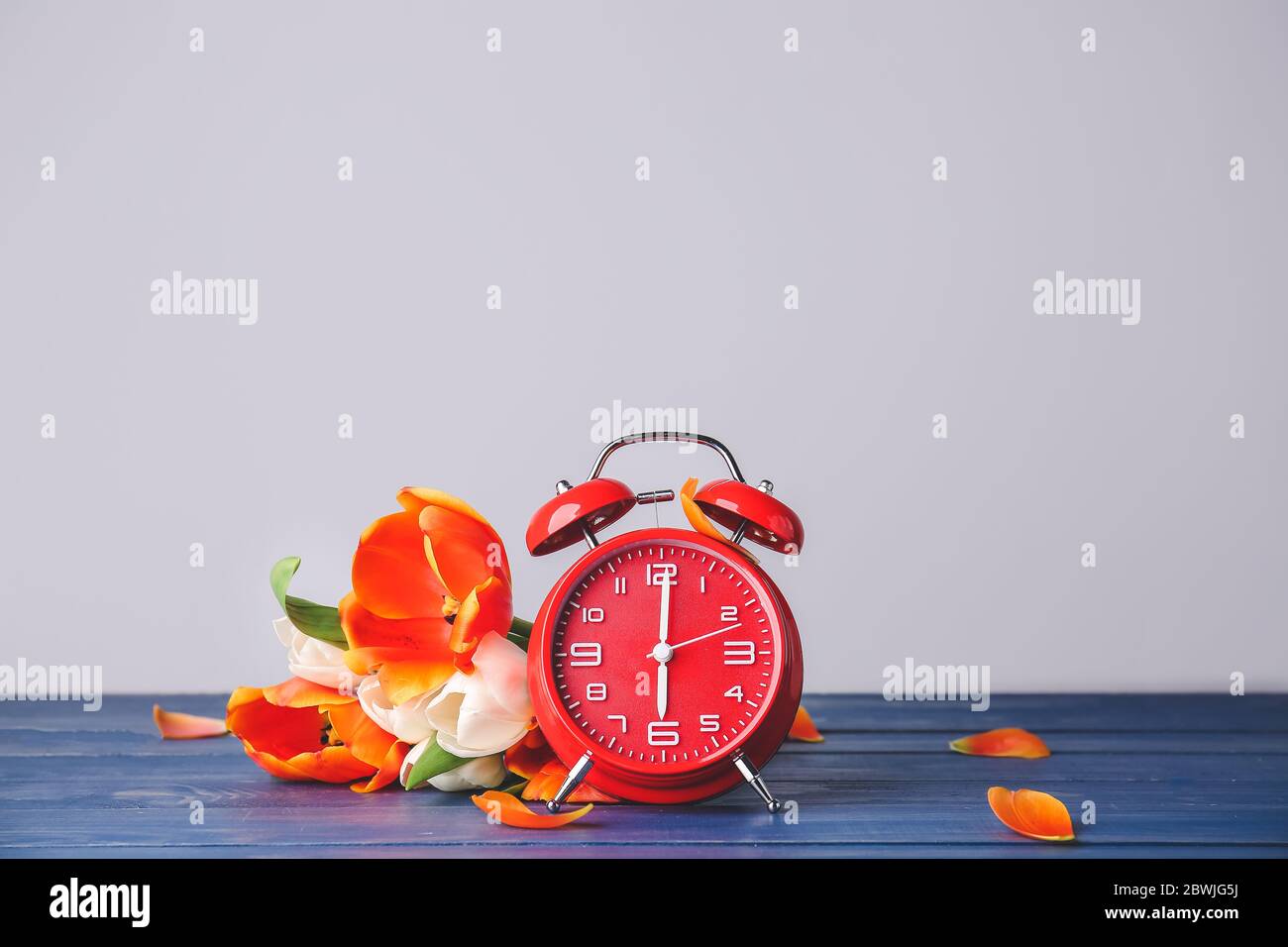 Alarm clock and flowers on table. Spring time Stock Photo - Alamy