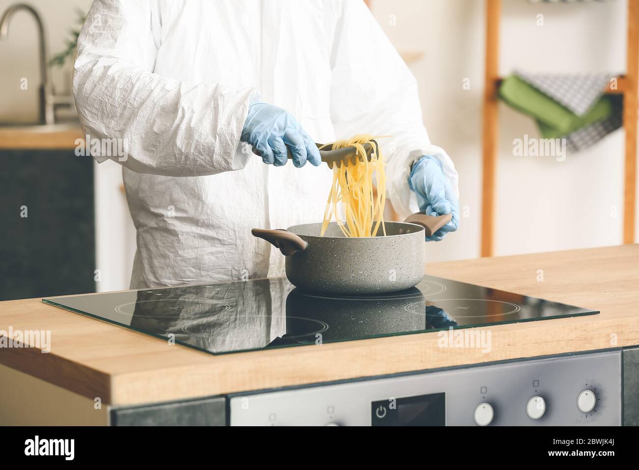Woman in biohazard suit cooking in kitchen Stock Photo - Alamy