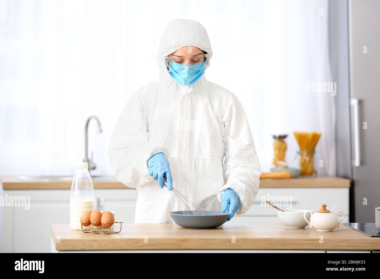 Woman in biohazard suit cooking in kitchen Stock Photo - Alamy
