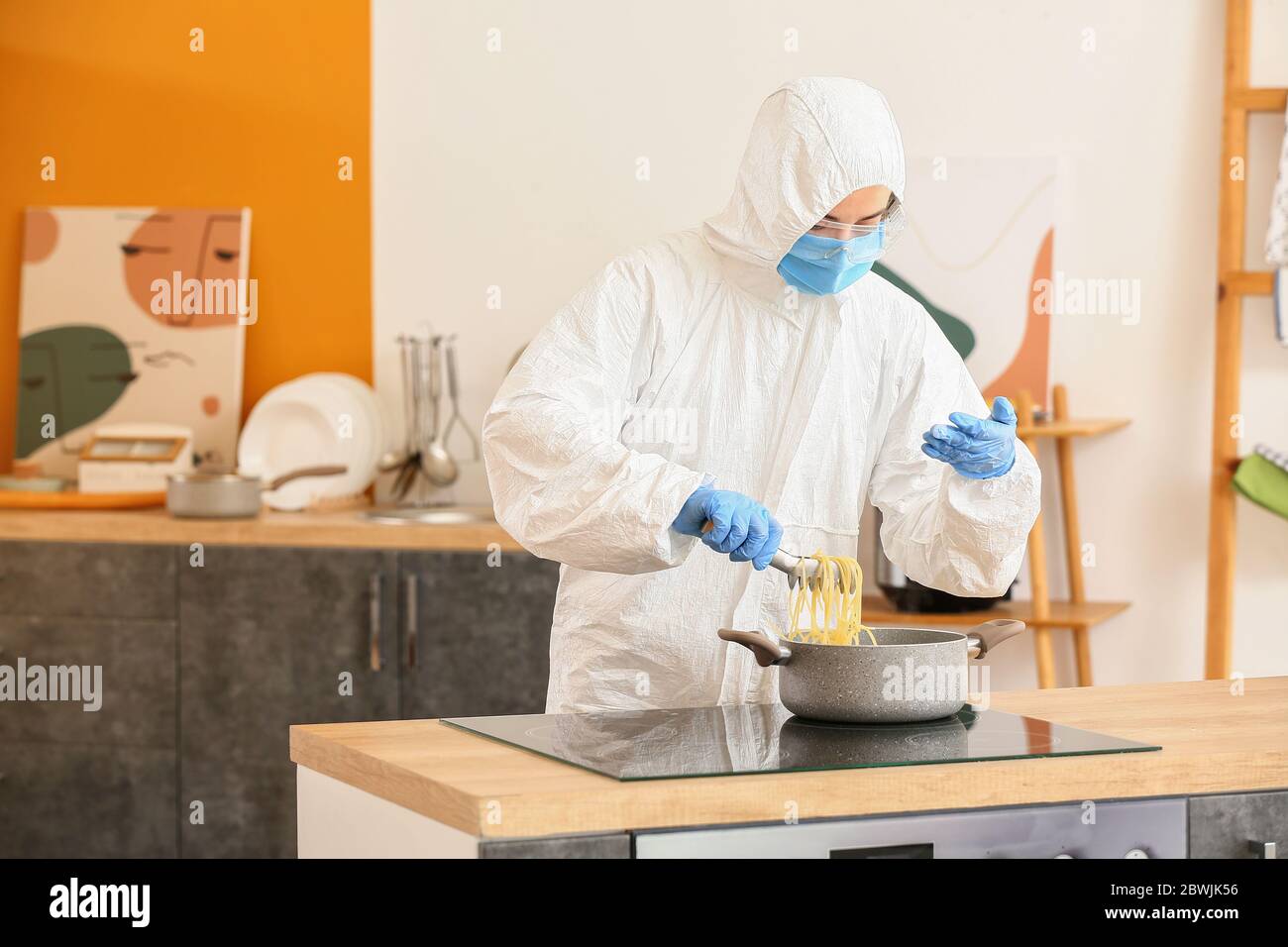 Woman in biohazard suit cooking in kitchen Stock Photo - Alamy