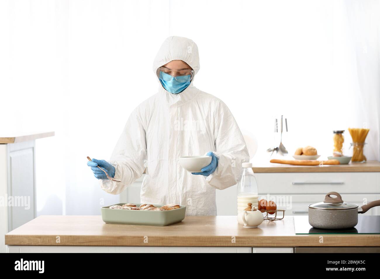 Woman in biohazard suit cooking in kitchen Stock Photo - Alamy