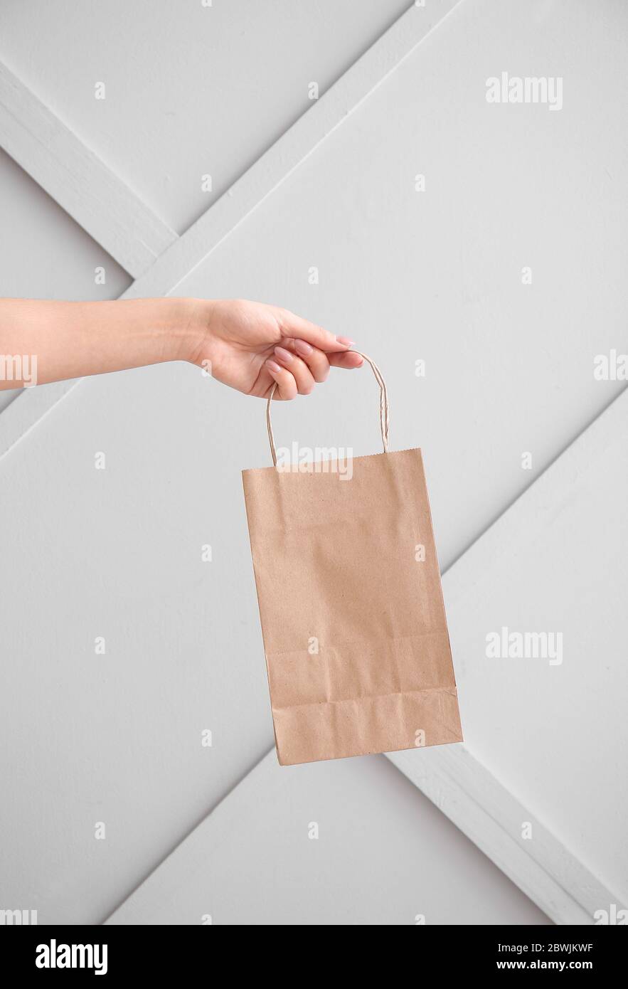 Hand with paper bag on light background Stock Photo - Alamy