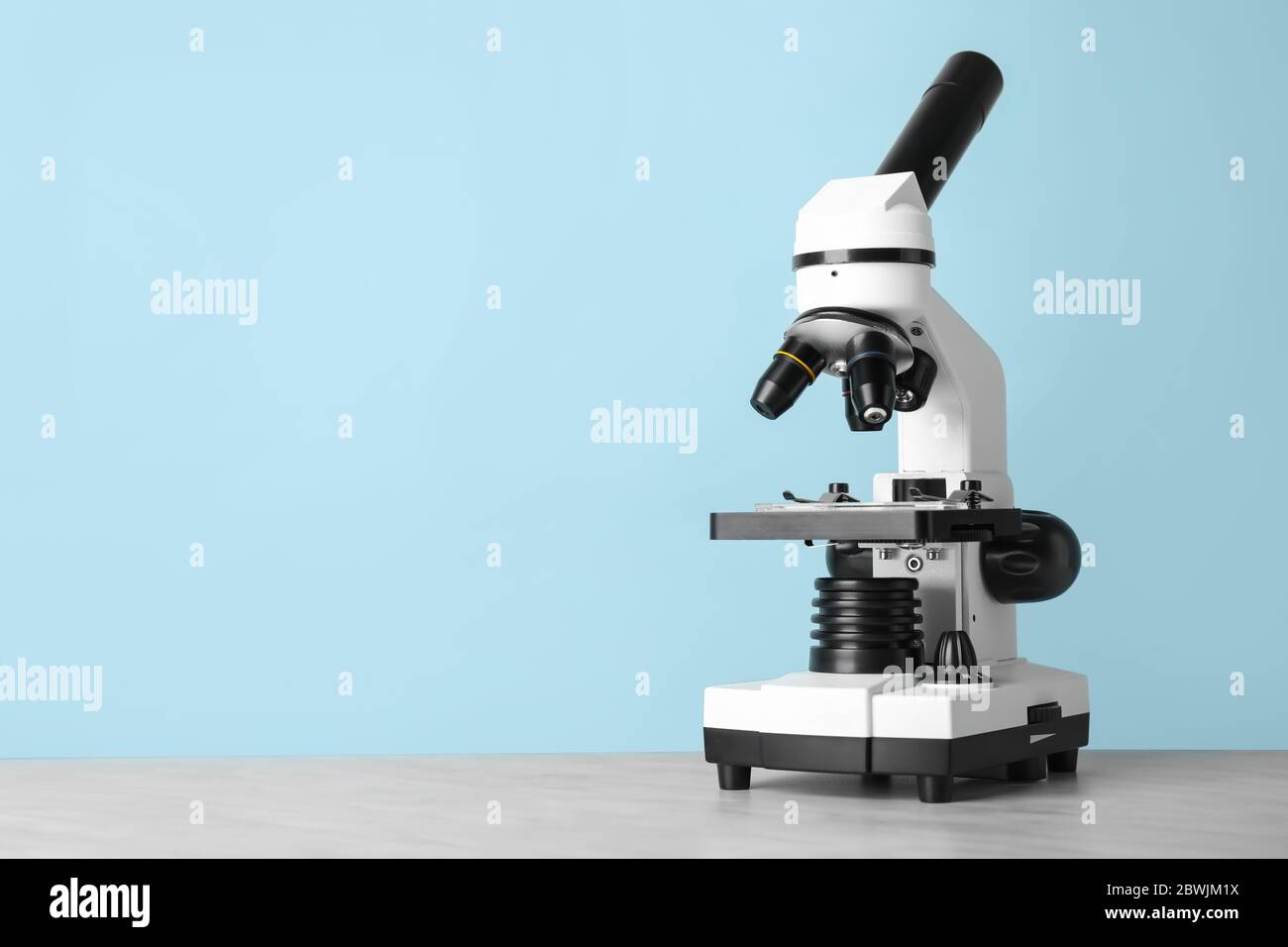 Modern microscope on table against color background Stock Photo - Alamy