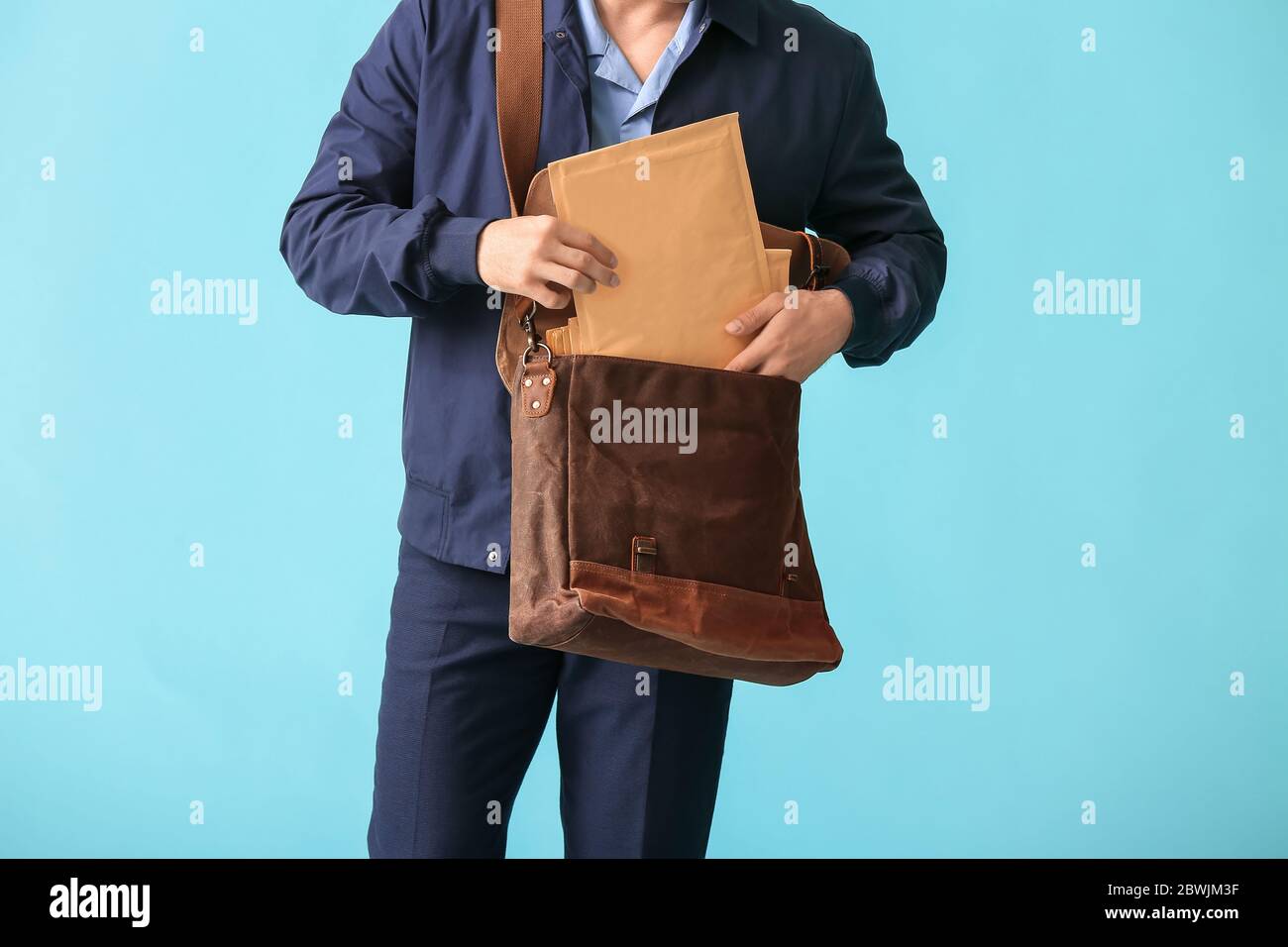 Handsome young postman on color background Stock Photo - Alamy