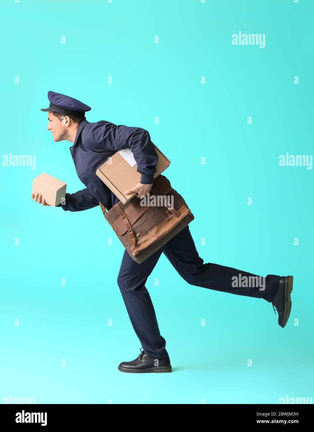 Handsome running postman on color background Stock Photo - Alamy