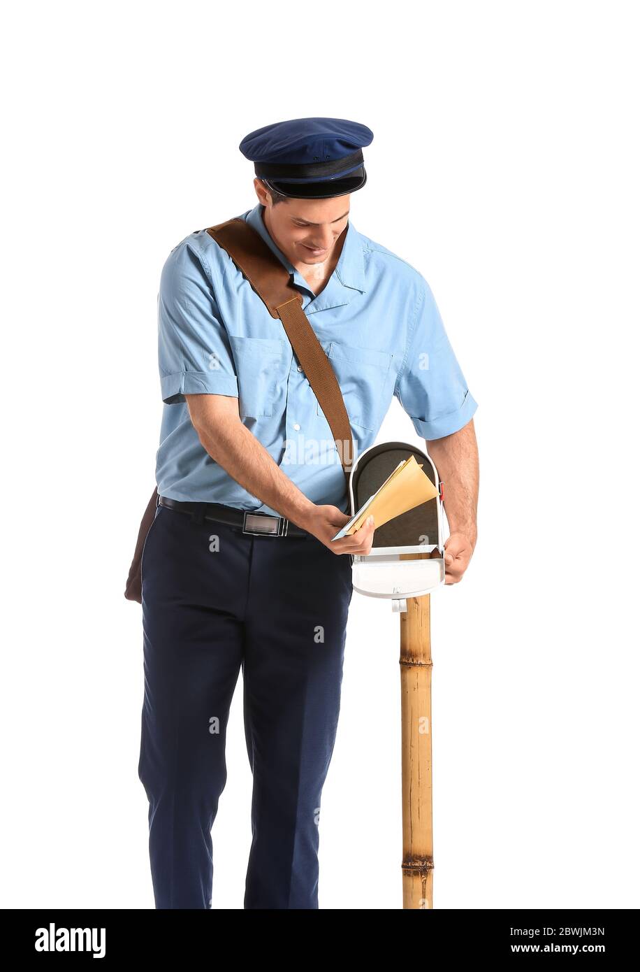 Handsome young postman putting letters in mail box on white background ...