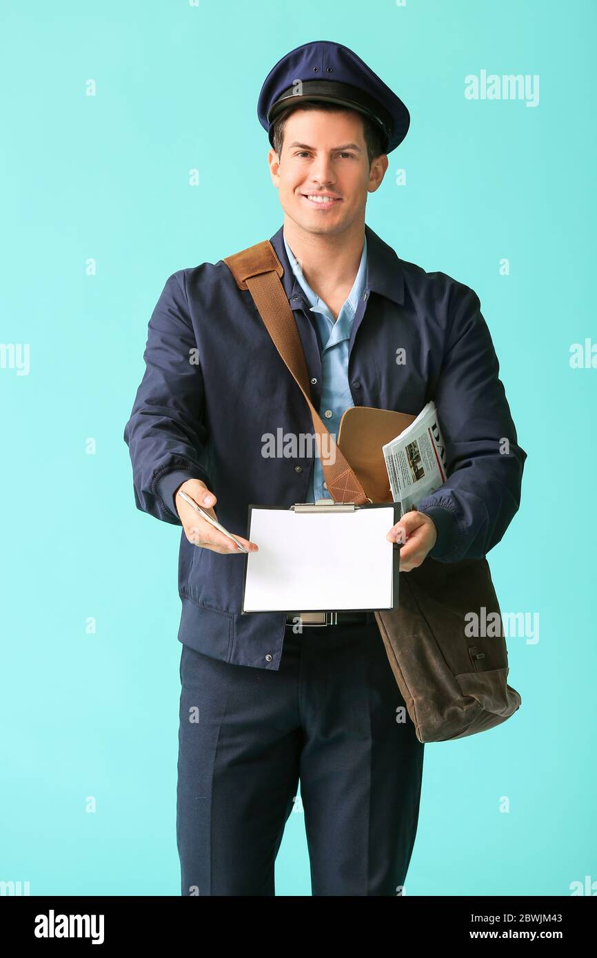 Handsome young postman on color background Stock Photo - Alamy