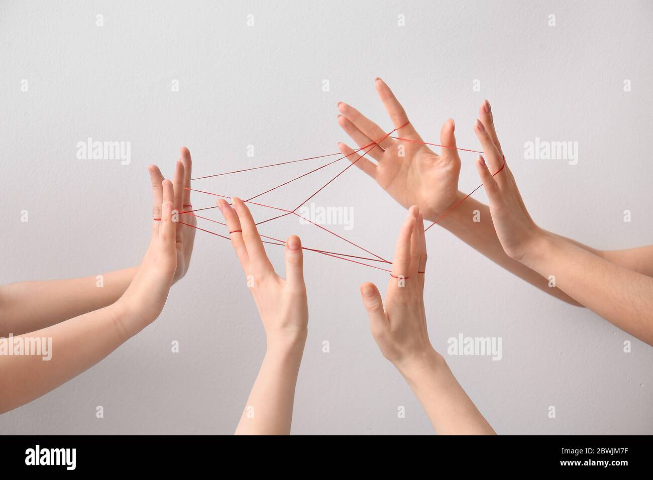 Hands tied with red thread on light background. Unity concept Stock ...
