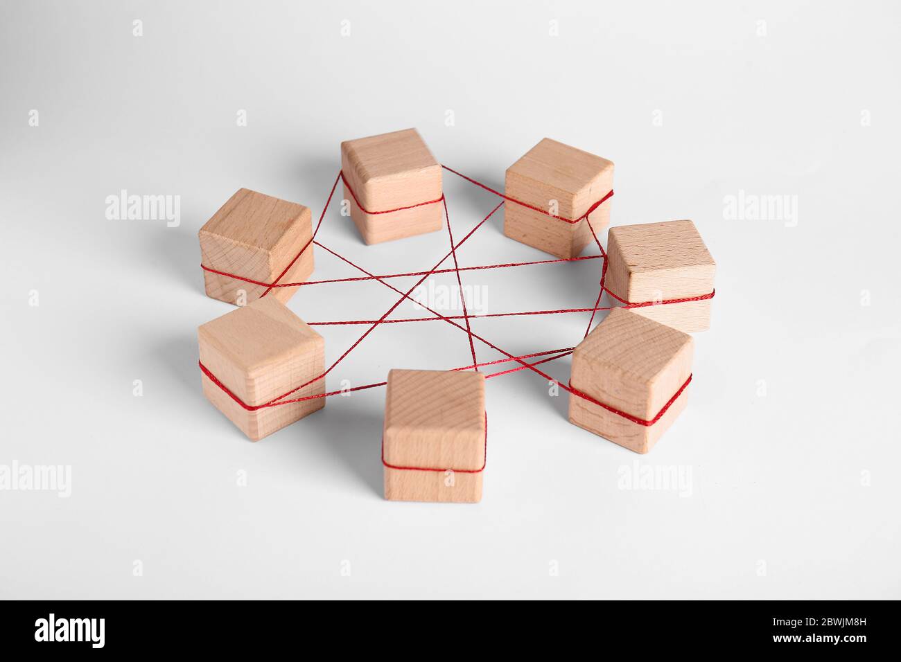 Wooden cubes tied with red thread on light background. Unity concept ...
