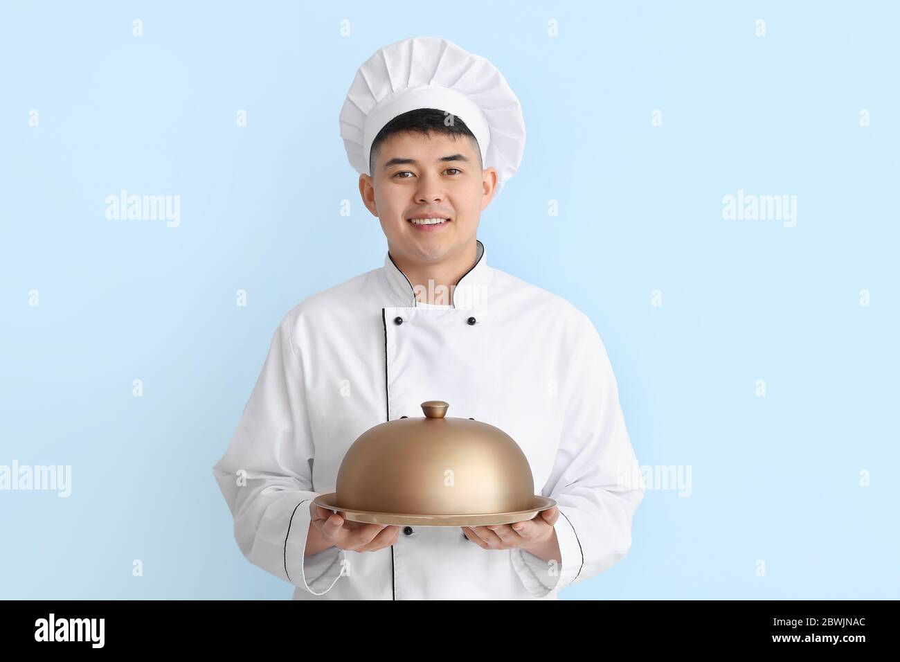 Handsome Asian chef with tray on color background Stock Photo - Alamy