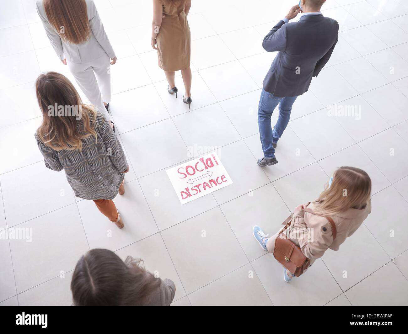 Group of people standing with social distance indoors. Concept of ...