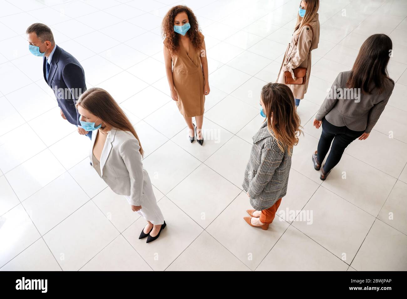 Group of people standing with social distance indoors. Concept of ...