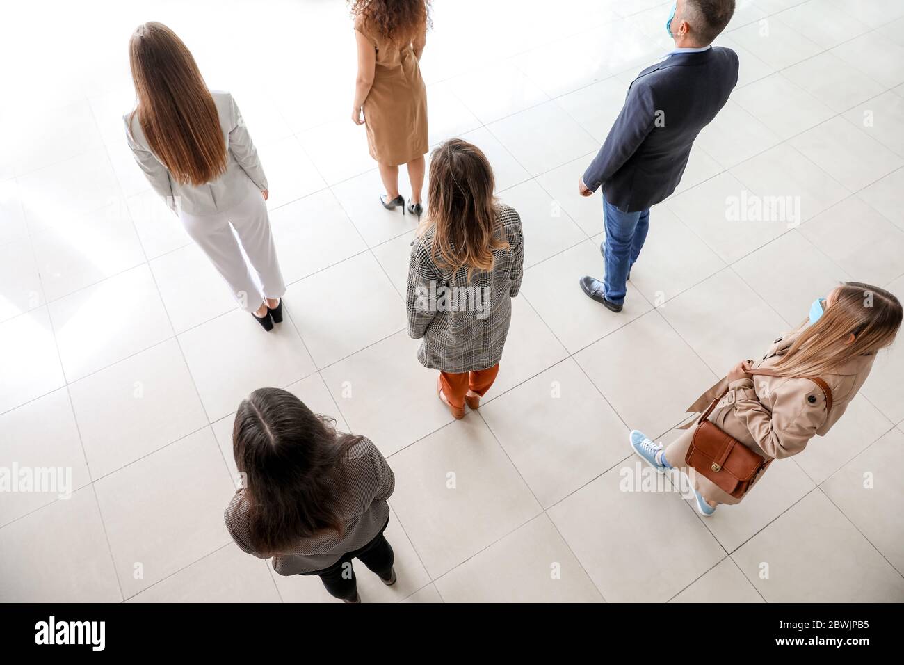 Group of people standing with social distance indoors. Concept of ...