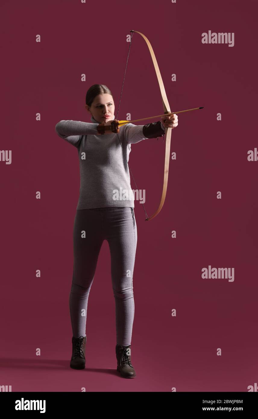 Beautiful woman with crossbow on color background Stock Photo - Alamy