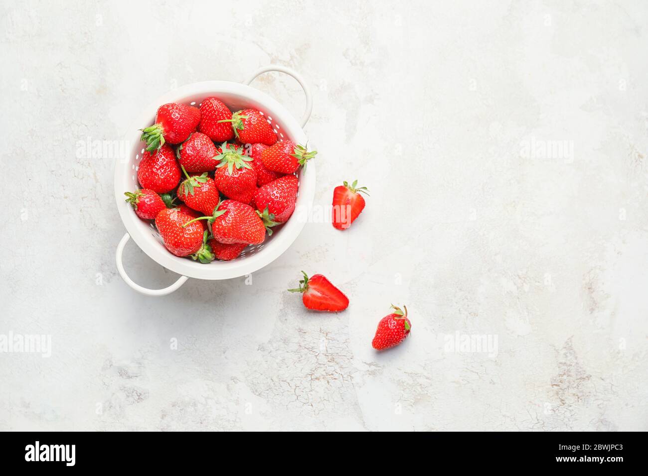 Colander with ripe strawberry on light background Stock Photo - Alamy