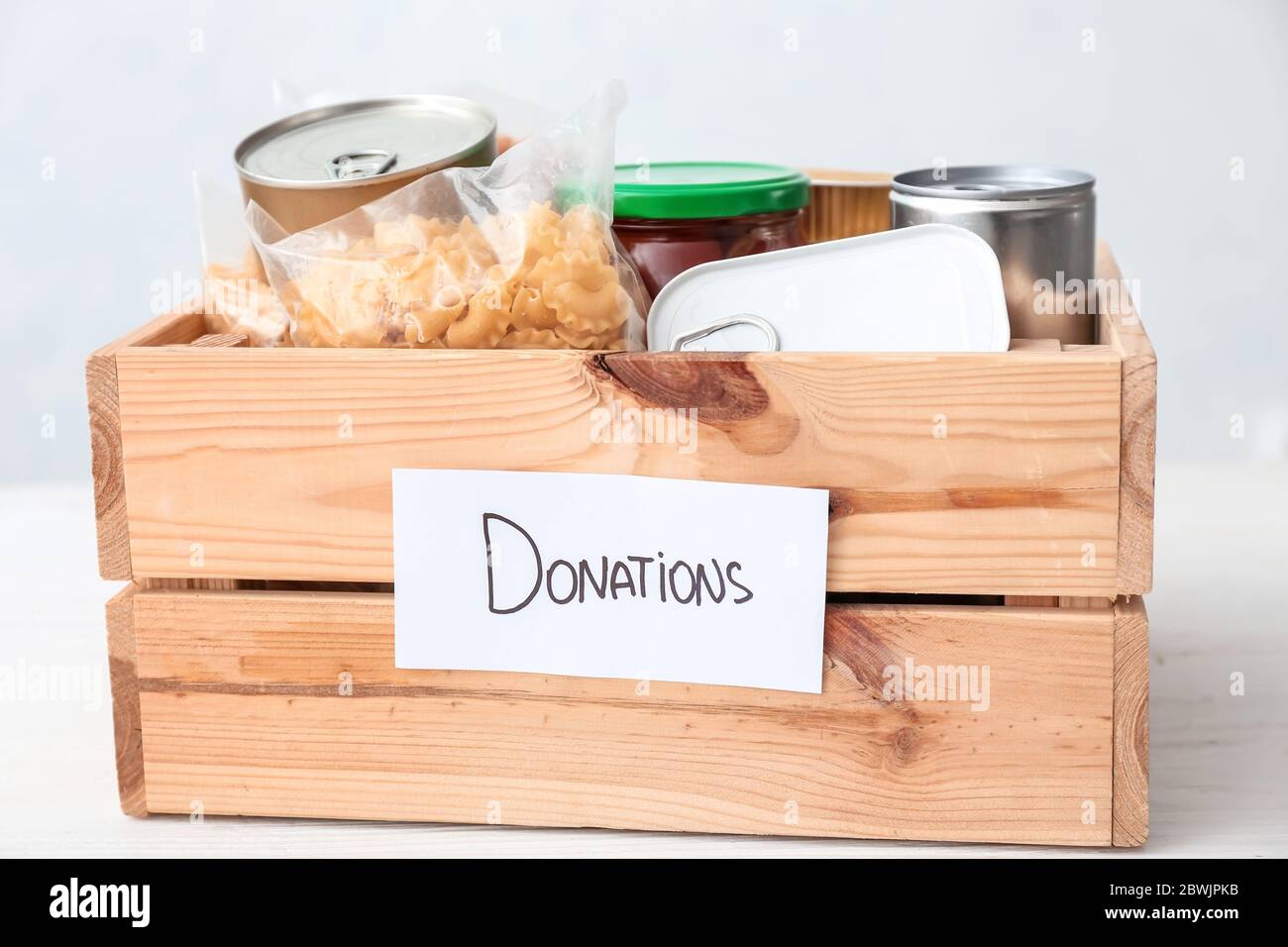 Box with donations on table against light background Stock Photo - Alamy