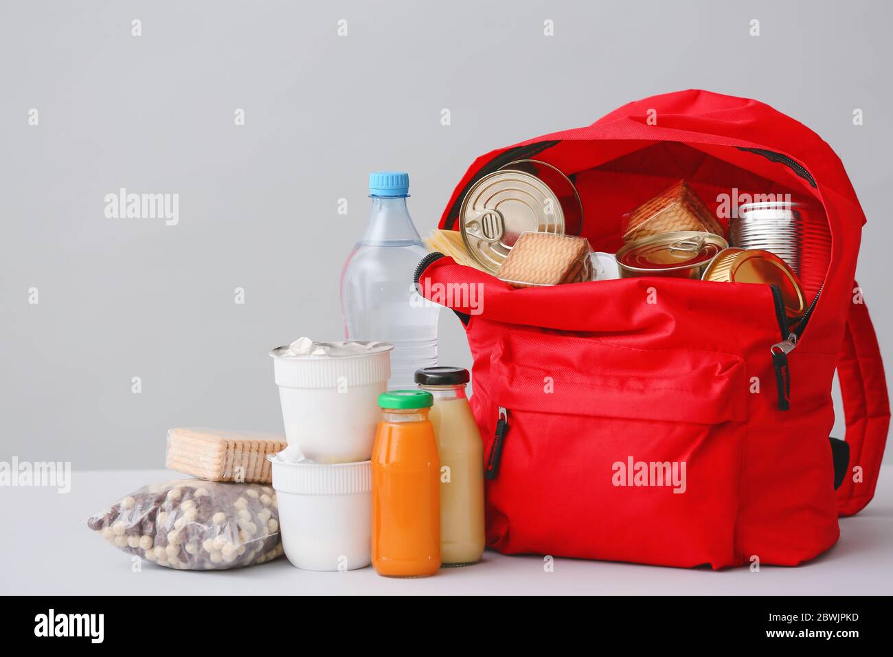 Schoolbag with different products on light background. Concept of ...