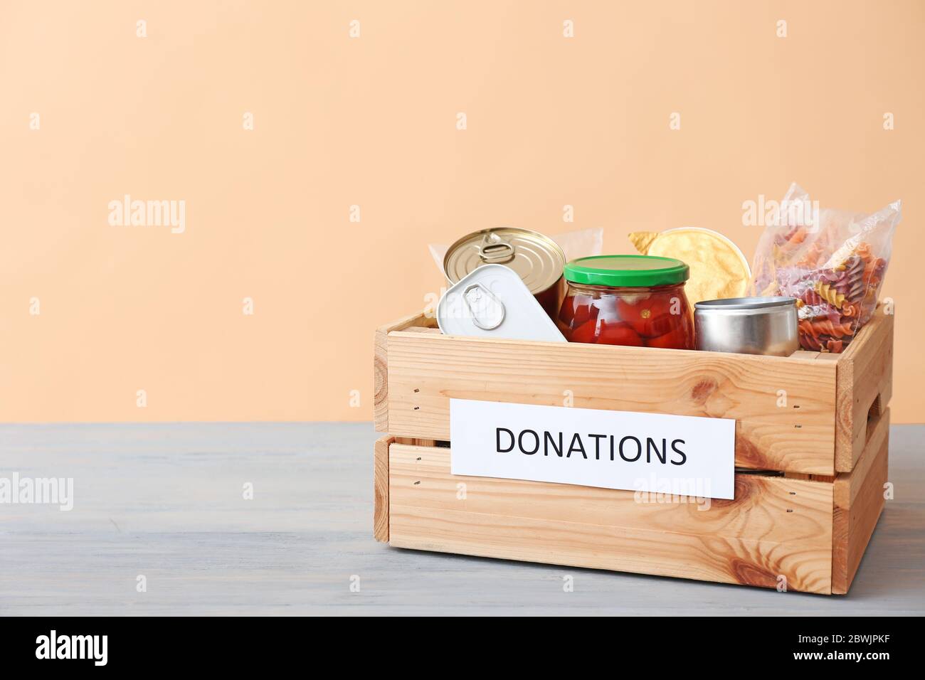 Box with donations on table against color background Stock Photo - Alamy