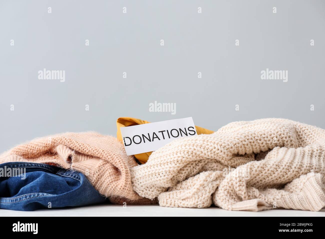 Different clothes and paper with word DONATIONS on light background ...