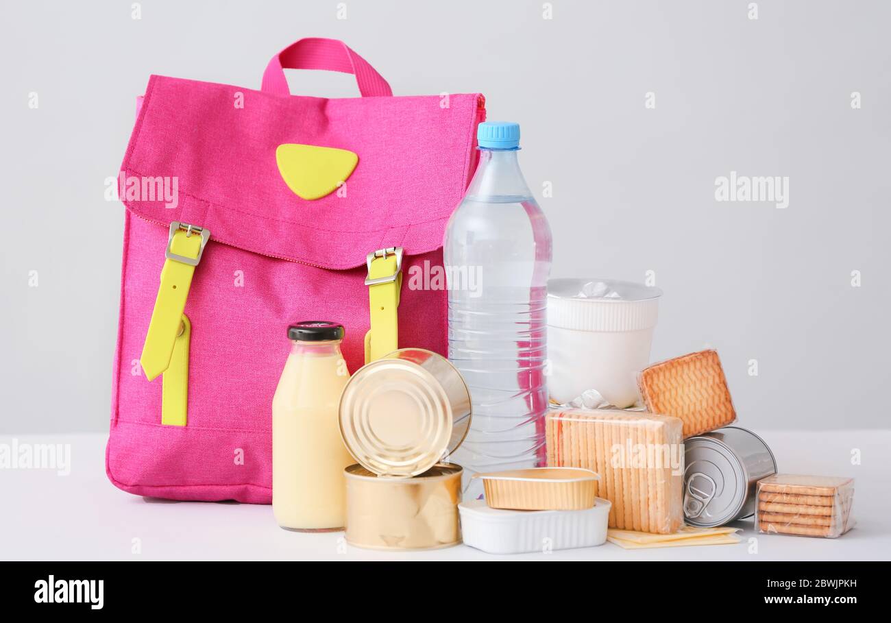 Schoolbag with different products on light background. Concept of ...