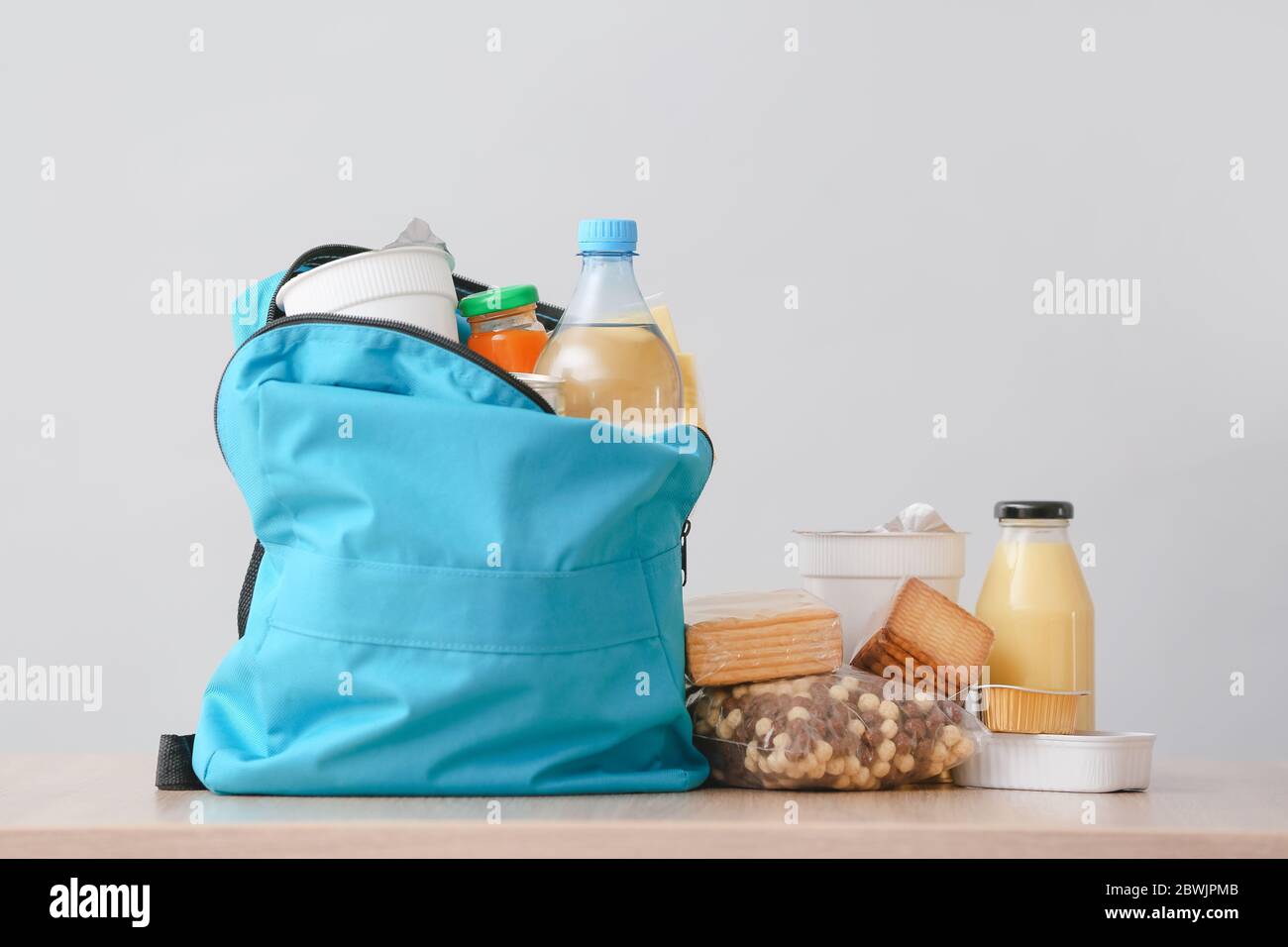Schoolbag with different products on light background. Concept of ...