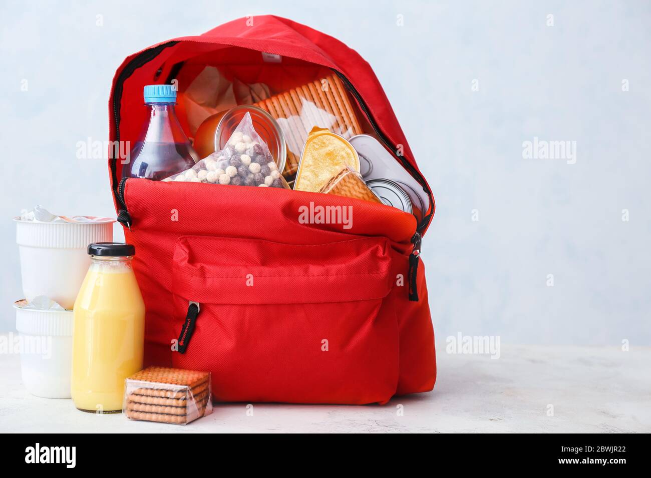 Schoolbag with different products on light background. Concept of ...