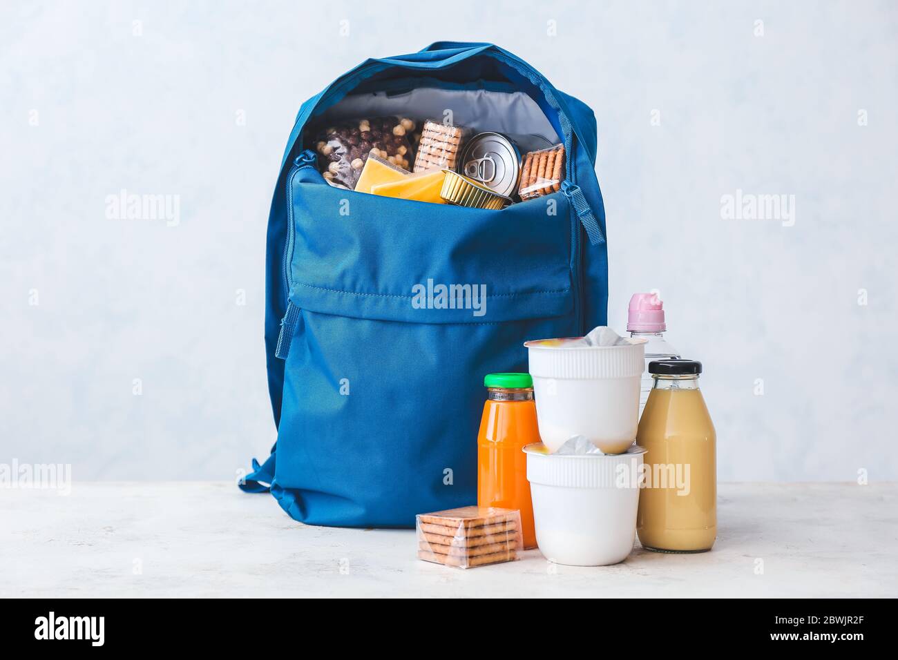 Schoolbag with different products on light background. Concept of ...