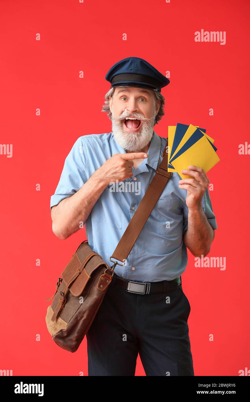 Surprised old postman on color background Stock Photo - Alamy
