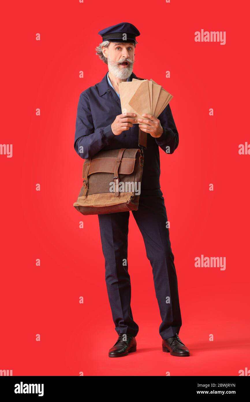 Surprised old postman on color background Stock Photo - Alamy