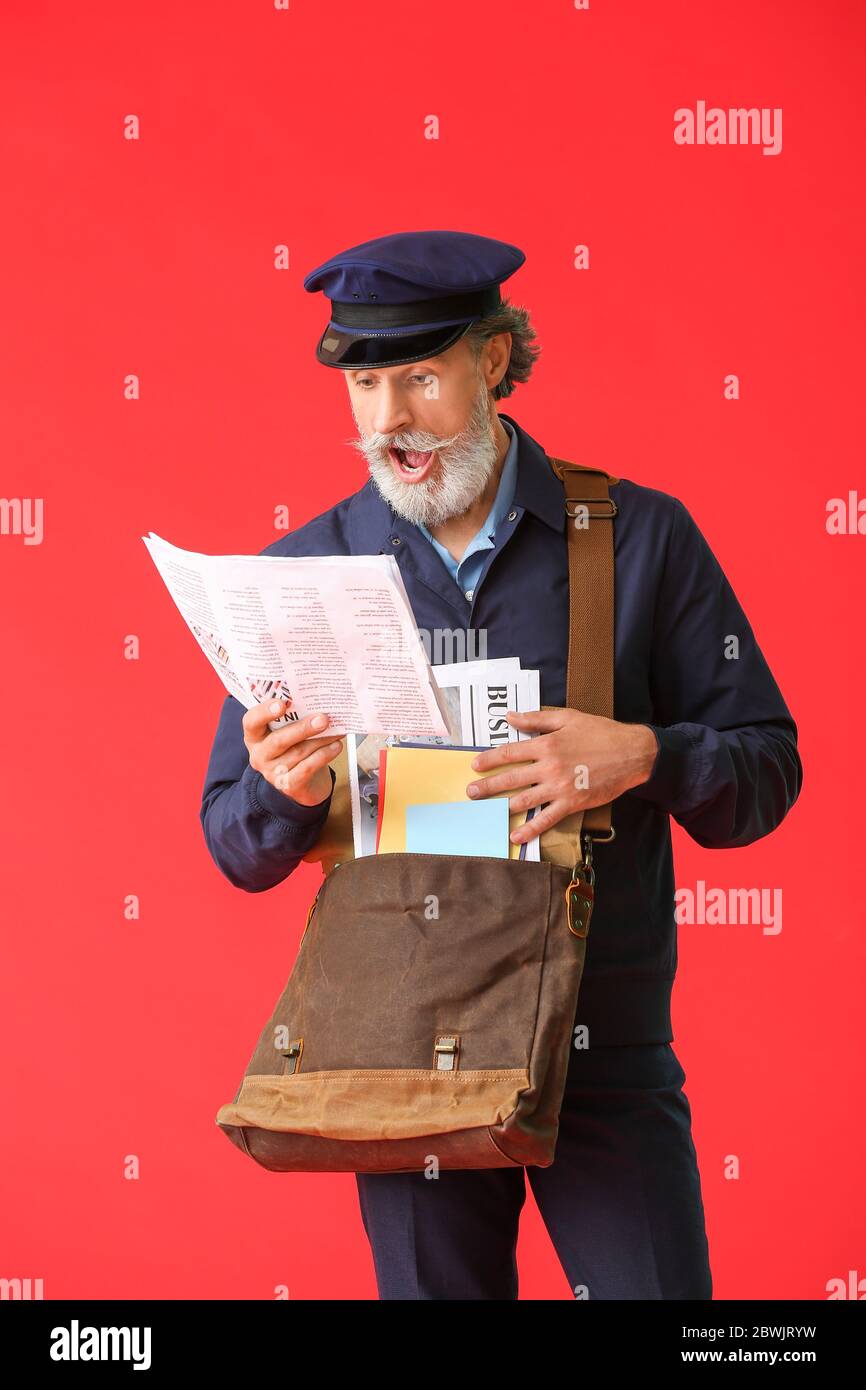 Surprised old postman on color background Stock Photo - Alamy
