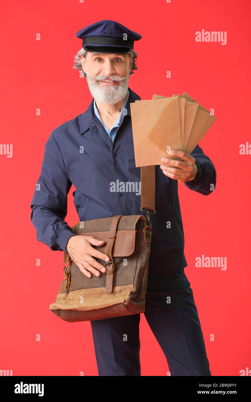 Handsome old postman on color background Stock Photo - Alamy