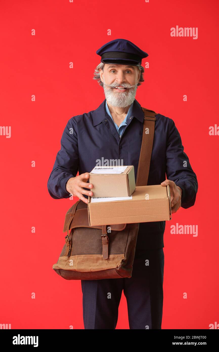 Handsome old postman on color background Stock Photo - Alamy