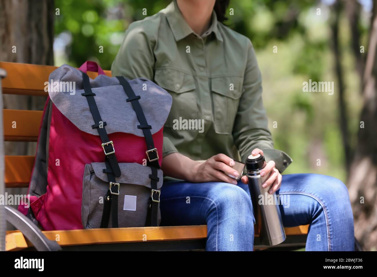 Female traveler with backpack sitting on bench in park Stock Photo - Alamy