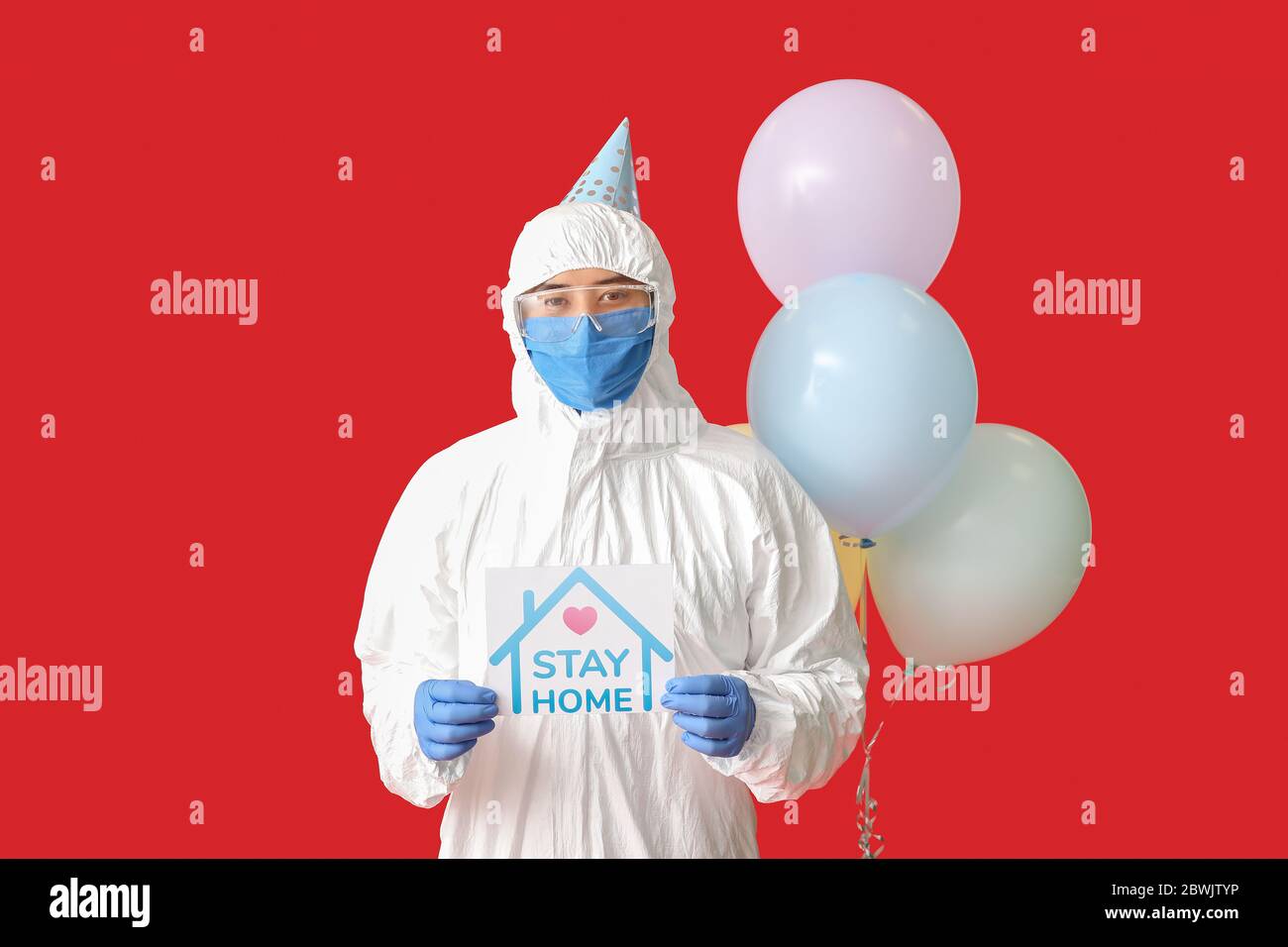 Asian man in biohazard suit and with Birthday balloons on color ...