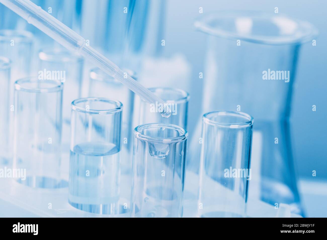 Laboratory glassware with a dropper dripping liquid into a test tube ...