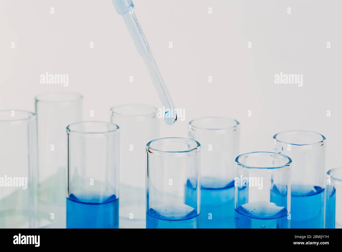 Laboratory glassware with a dropper dripping liquid into a test tube ...