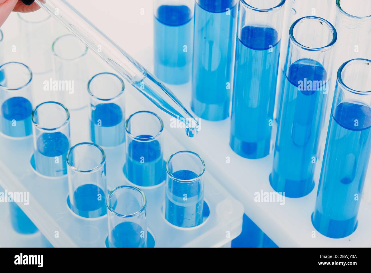 Laboratory glassware with a dropper dripping liquid into a test tube ...