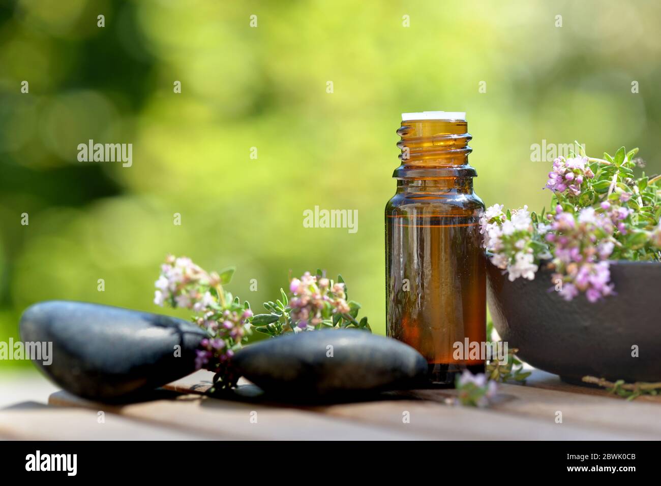 bottle of essential oil and flowers of aromatic herb and pebbles on a ...