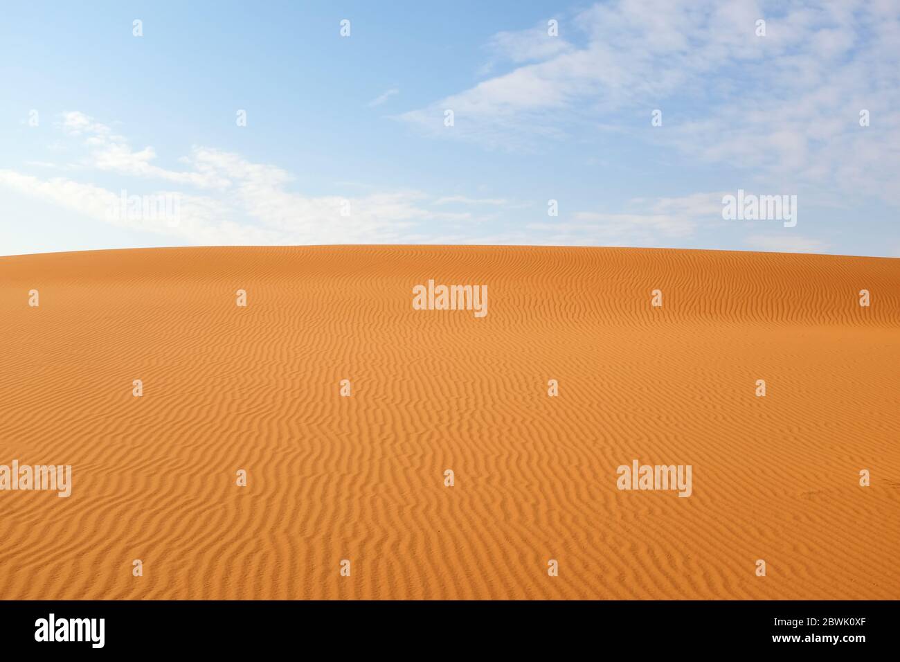 Bright orange desert sand pattern ripples and clear blue sky for a warm ...