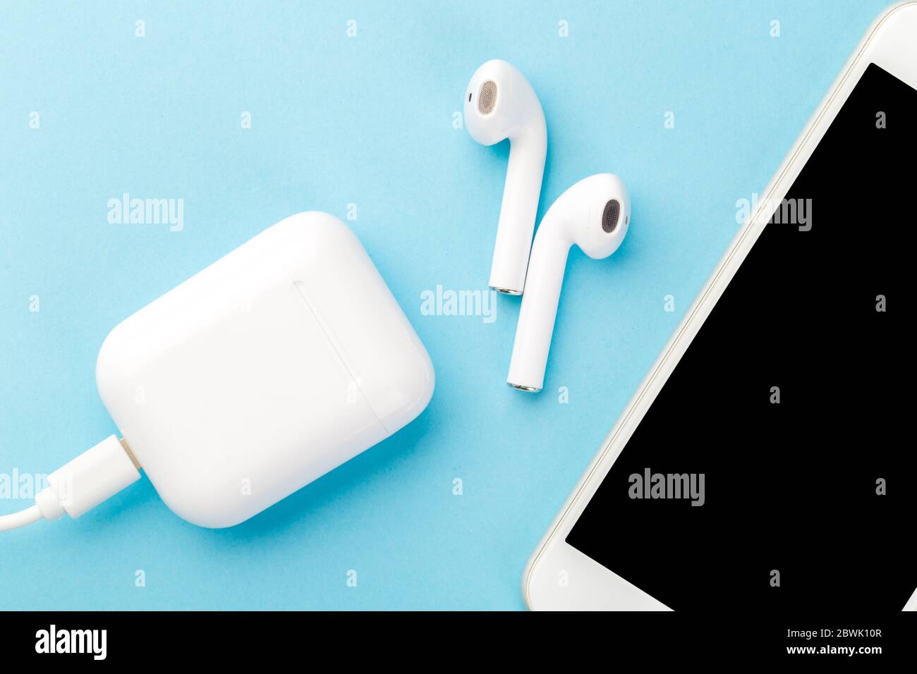 Wireless bluetooth headphones with a modern mobile phone on a blue ...