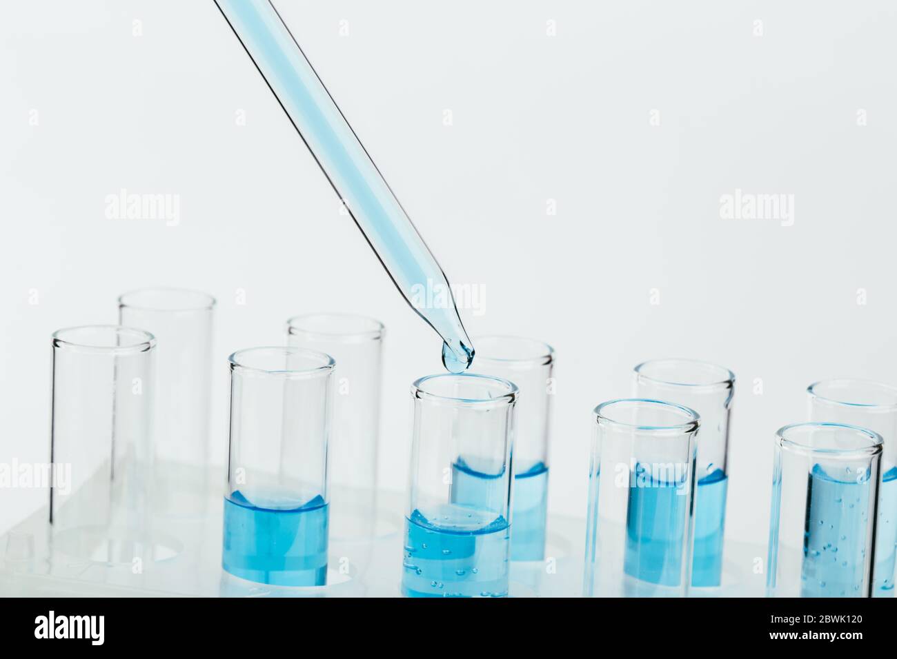 Laboratory glassware with a dropper dripping liquid into a test tube ...