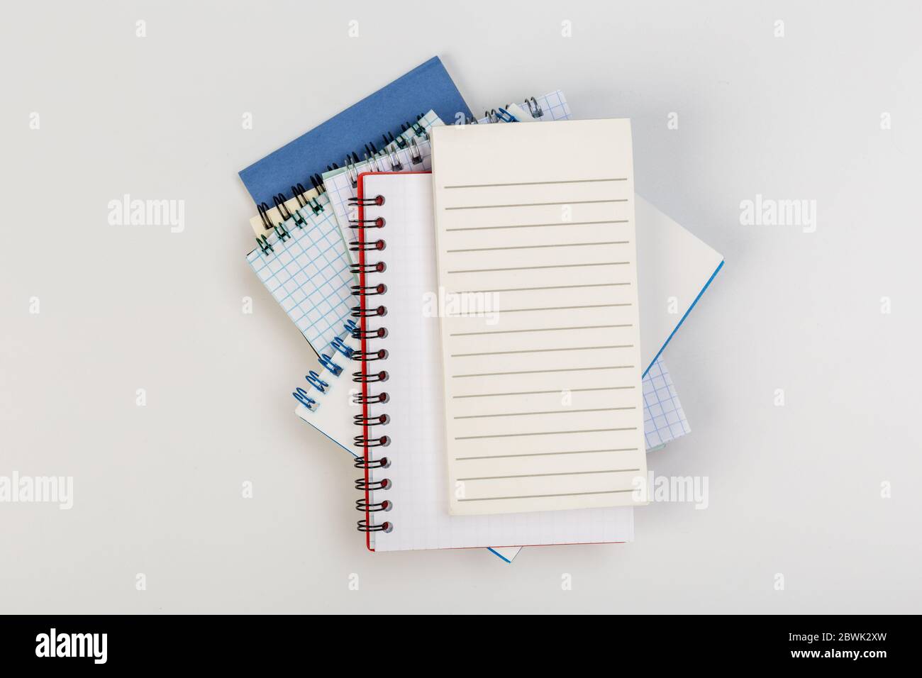 a stack of several spiral school notebooks lies on a white table with a ...