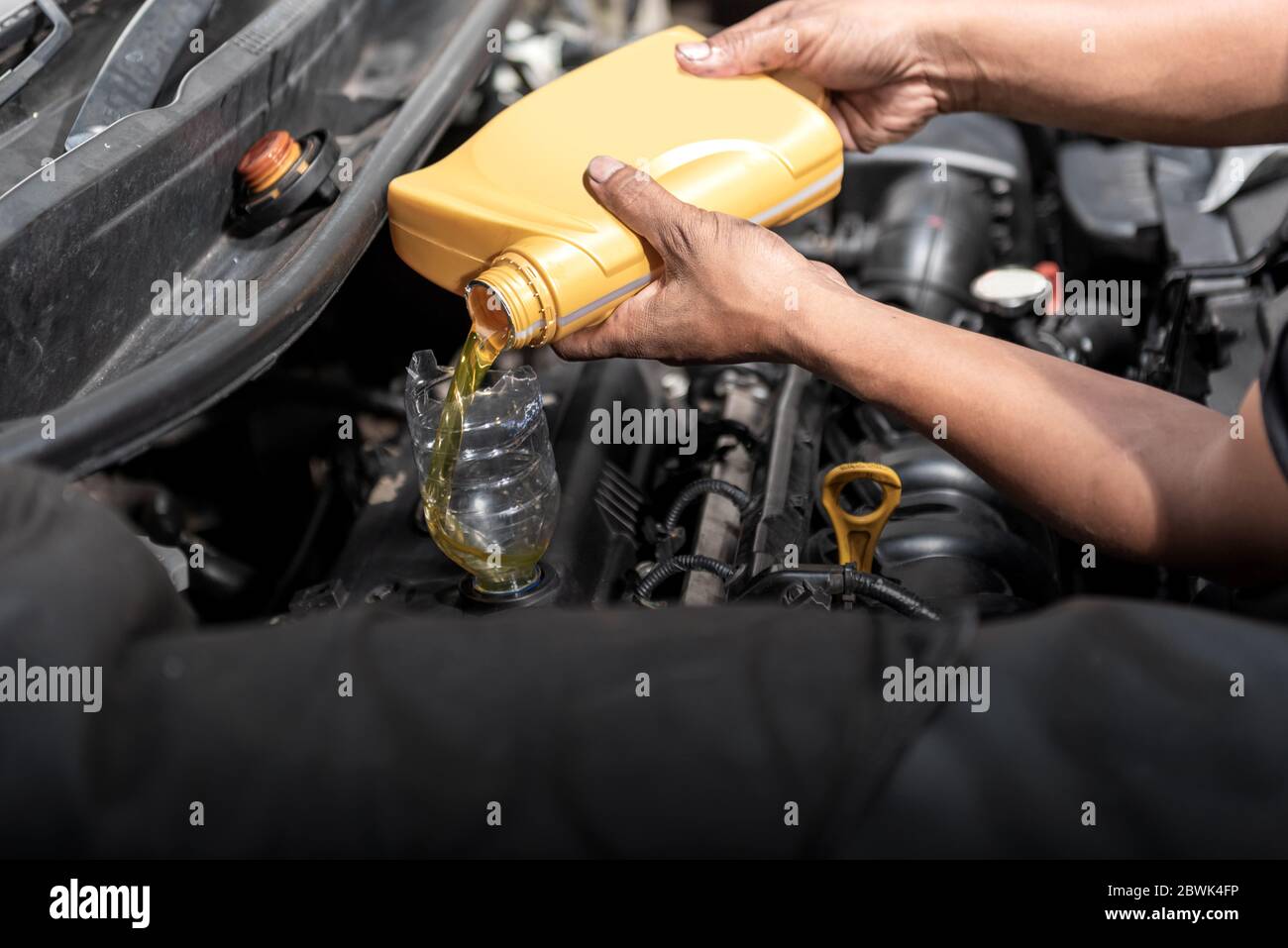 Car mechanic pour the oil to the car engine on the garage Stock Photo ...