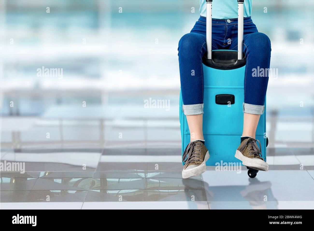 The woman sitting on suitcase on the airport Stock Photo - Alamy
