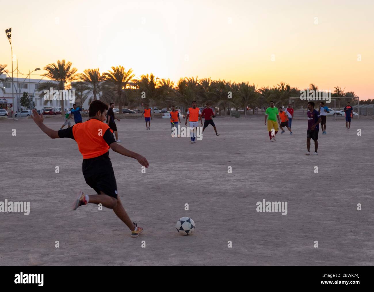 Young men playing football in Al Ghubra suburb at sunset, Muscat, Oman ...