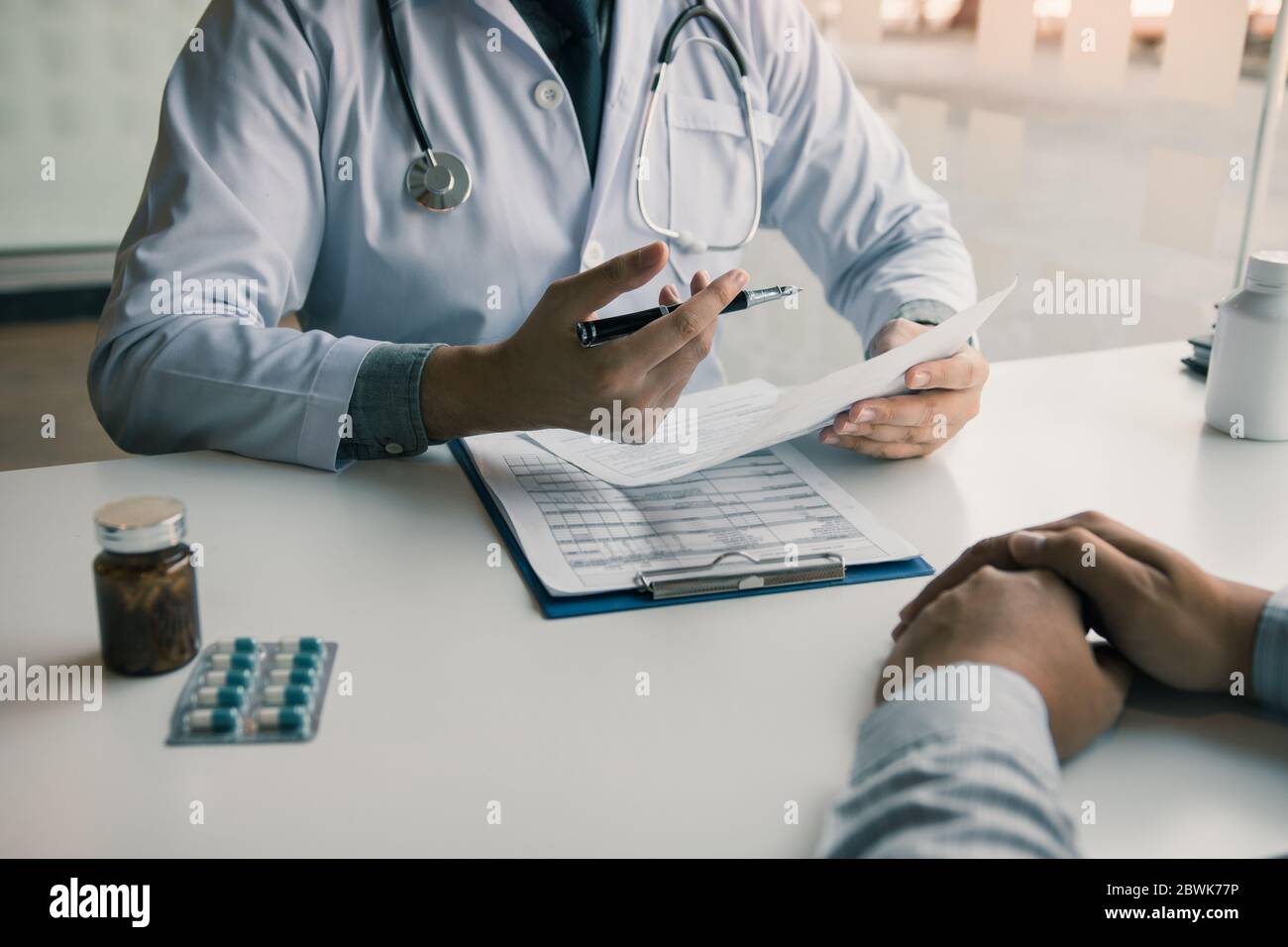 Doctor hand holding pen writing patient history list on note pad and ...