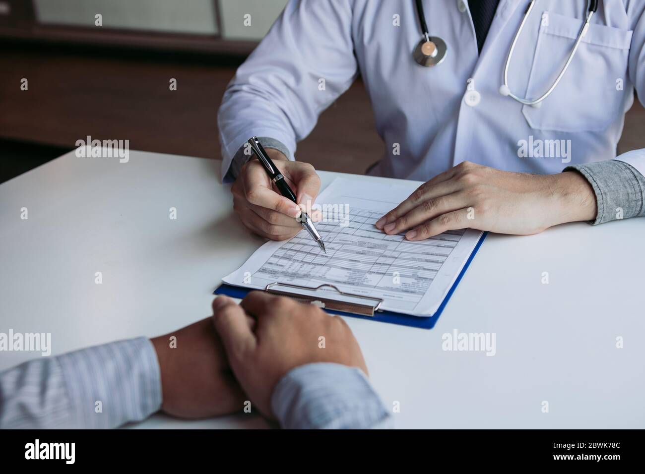 Doctor hand holding pen and talking to the patient about medication and ...